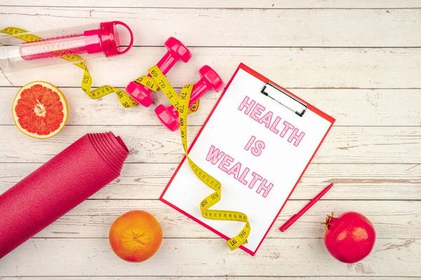 Healthy lifestyle concept. Clipboard with note Health is Wealth, water ...