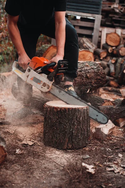 Young man works with a chainsaw on backyard - Stock Image - Everypixel