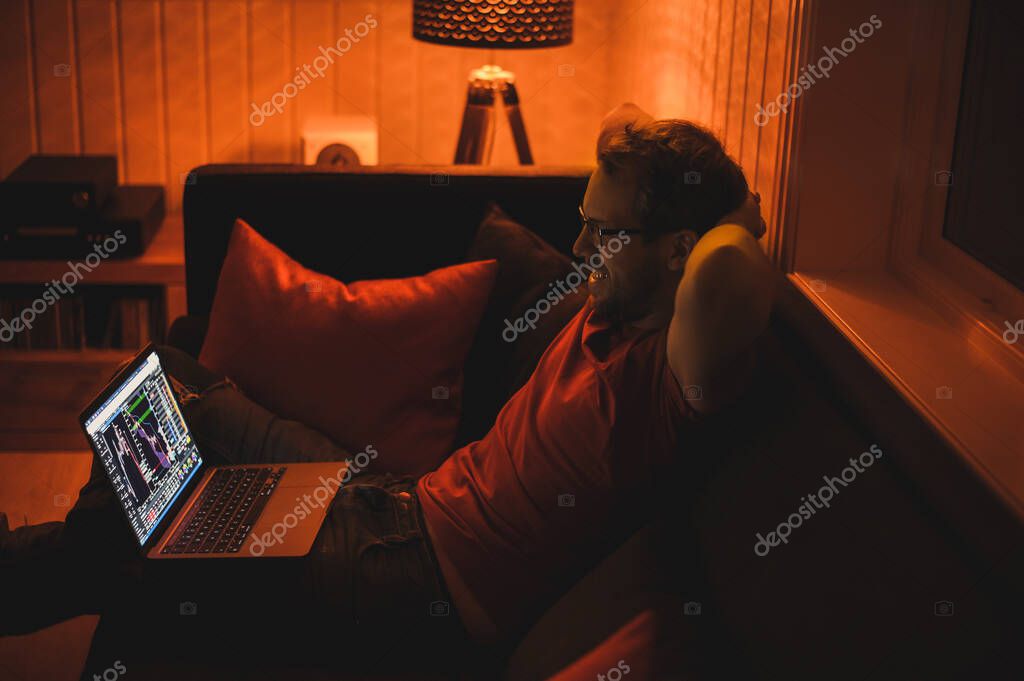 Portrait of attractive nerdy man is working late night on the computer ...