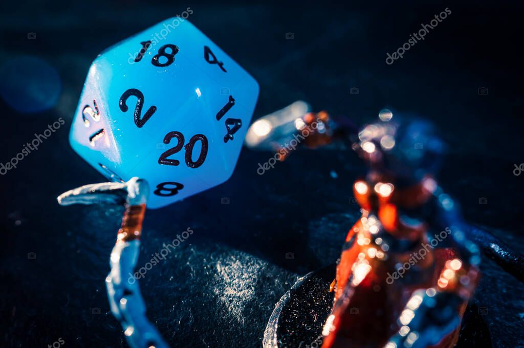 Primer plano de un dado azul de veinte lados y un papel que juega mini ...