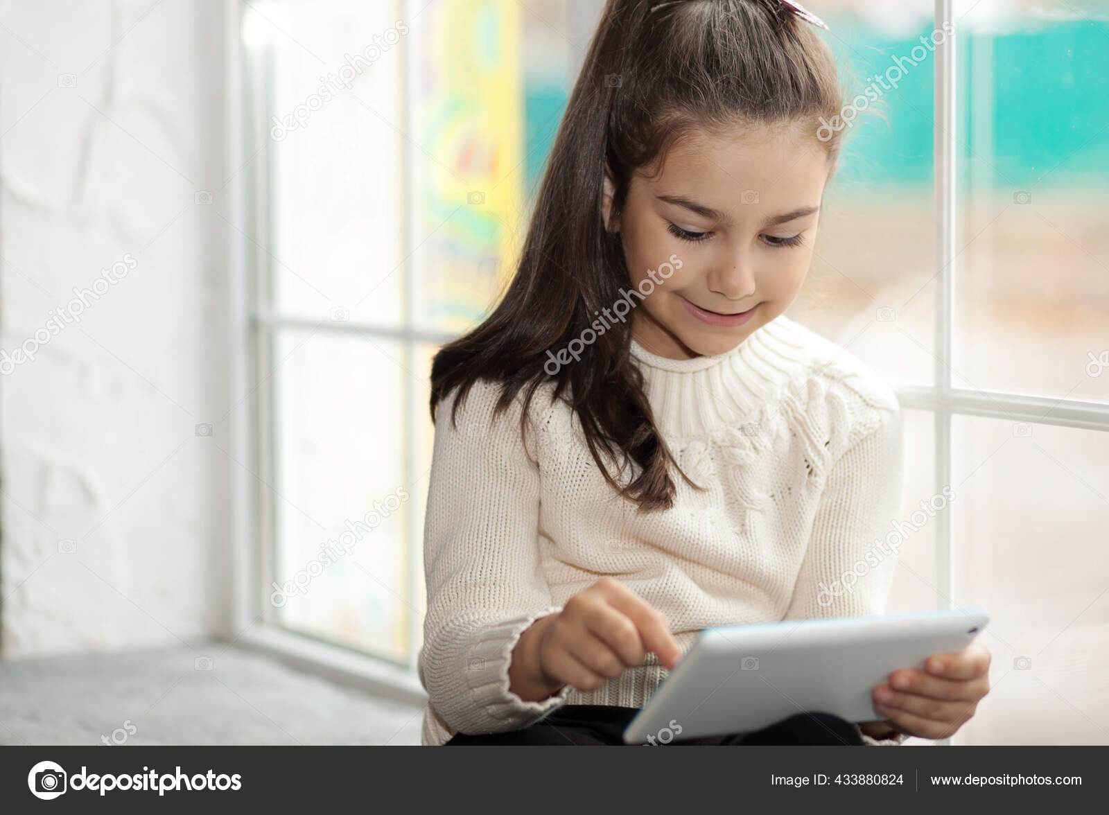 Cute Little Girl Using Tablet While Sitting Window Home Stock Photo by ...