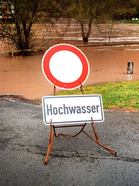 Señal de advertencia con letras Hochwasser (engl. ) cerca de la orilla ...