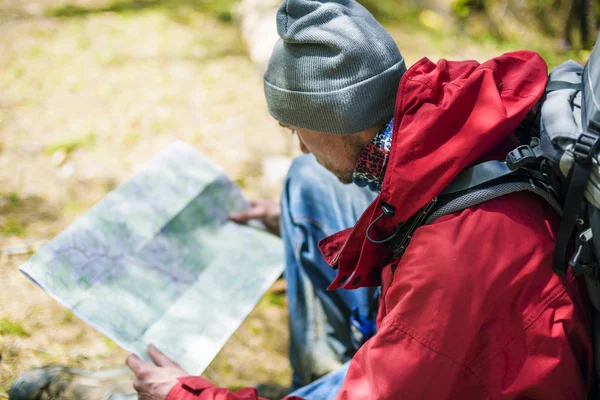 young caucasian male with a map in the forest, hiker looking at map ...