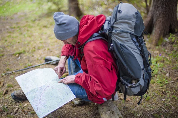Young caucasian male with a map in the forest, hiker looking at map ...