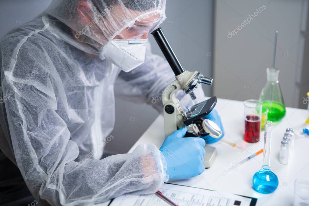 Profesional médico en traje protector blanco mirando a través del ...