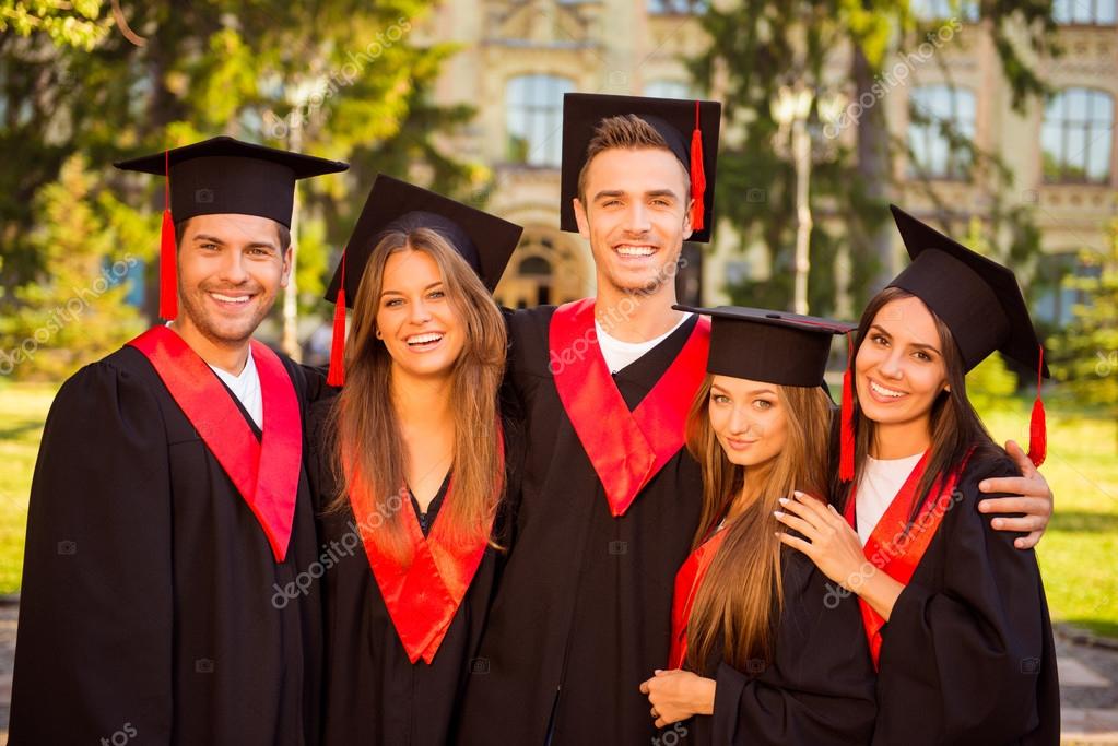Successful joyful five graduates in robes and hats smiling and h ...