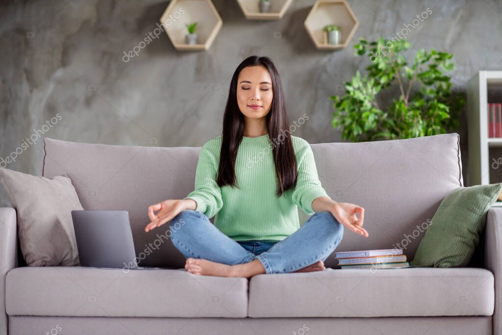 Foto de tamaño completo de la calma enfocada chica coreana sentarse sofá piernas cruzadas ...