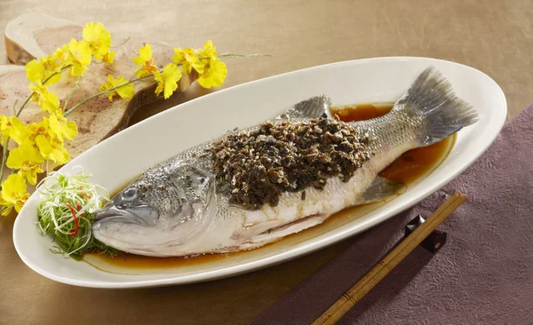 Meicai steamed fresh water fish grouper with sauce on white plat ...