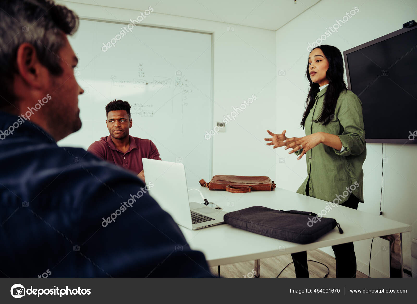 Female executive presenting project to manager and clients standing ...