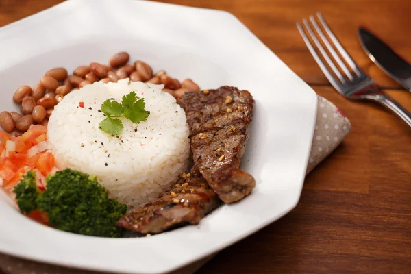 Grilled meat, rice and beans — Stock Photo © diogoppr #69744107