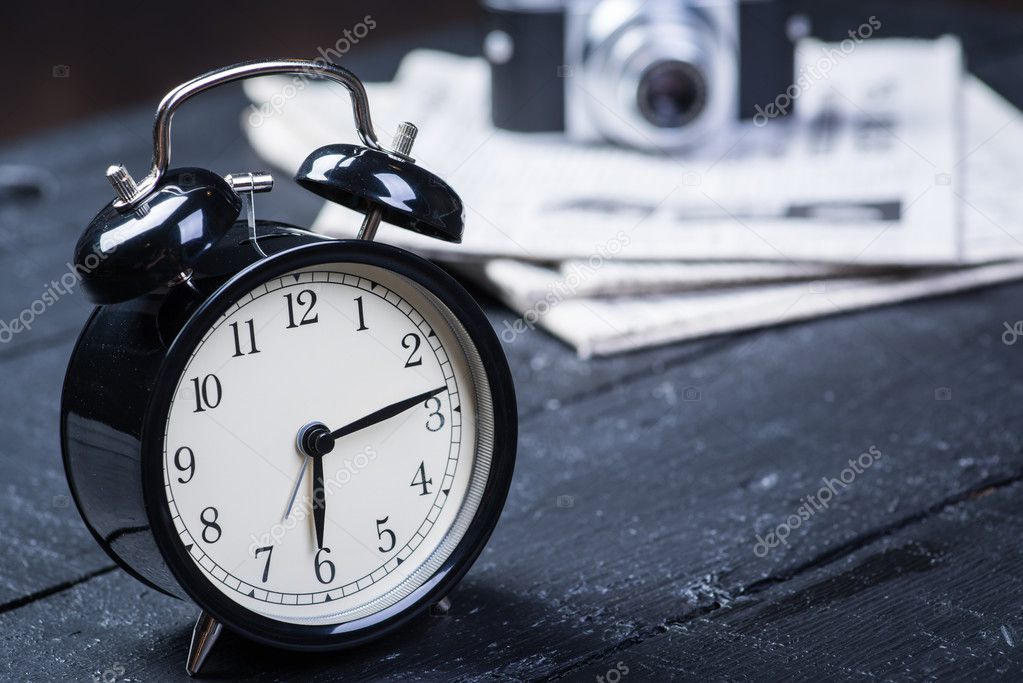 Black alarm clock with camera and newspaper on a wooden table — Stock ...