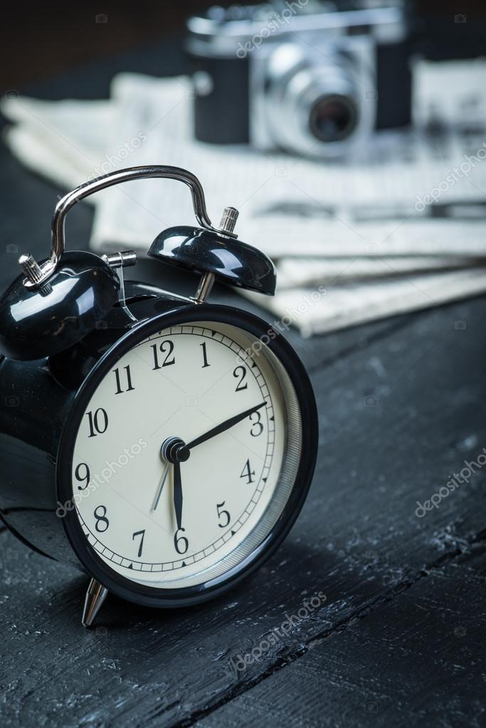Black alarm clock with camera and newspaper on a wooden table — Stock ...