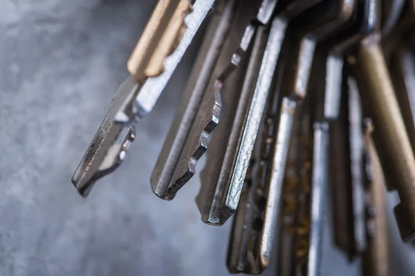 A bunch of old worn keys on the grey concrete wall — Stock Photo ...