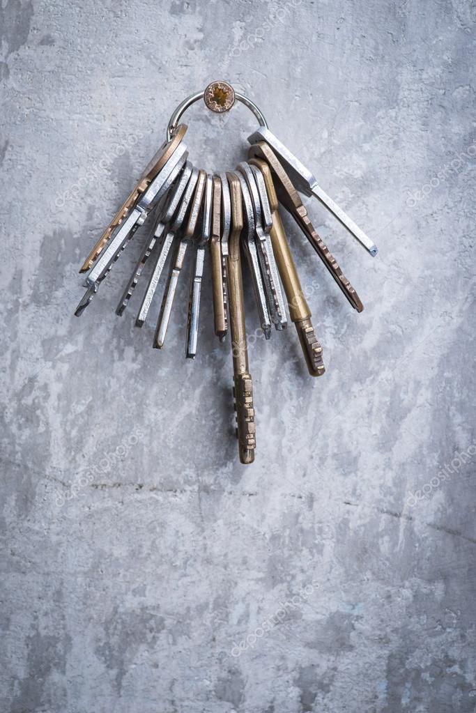 A bunch of old worn keys on the grey concrete wall — Stock Photo ...