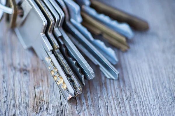 A bunch of old worn keys with metal house on the wooden surface — Stock ...