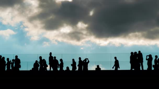 Unrecognizable people silhouettes walking on bridge against dramatic ...