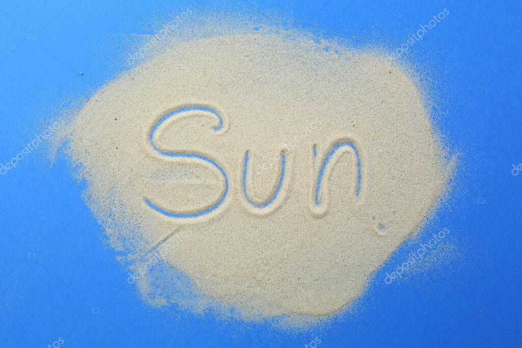 La palabra sol está escrita en la arena sobre un fondo azul. 2022