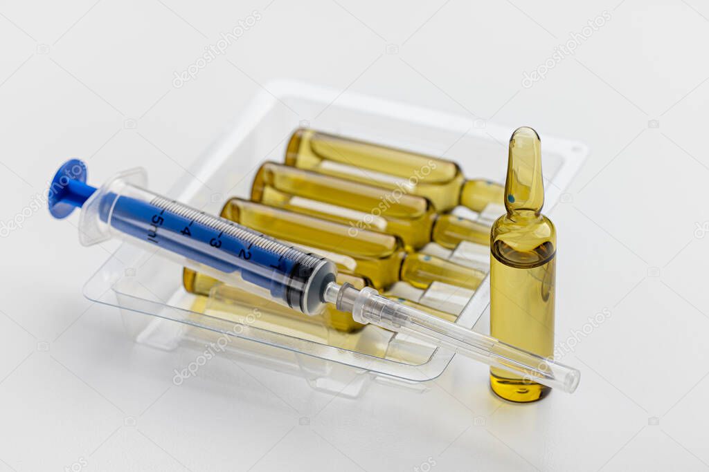 Ampollas de vidrio con una preparación inyectable y una jeringa azul ...