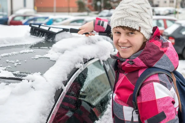 Female driver is cleaning snow with brush from the car roof - Stock ...