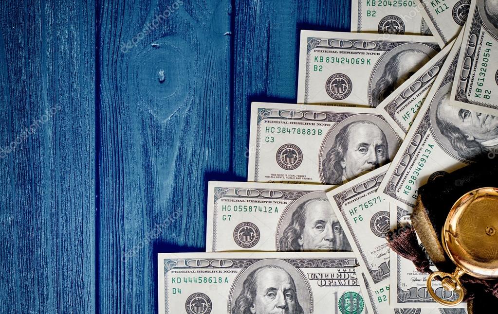 Stack of money dollars laid out like a ladder with antique gold watch ...