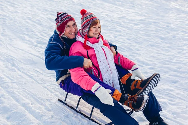 Sleigh. Senior couple sledding downhill. Family having fun sitting on ...