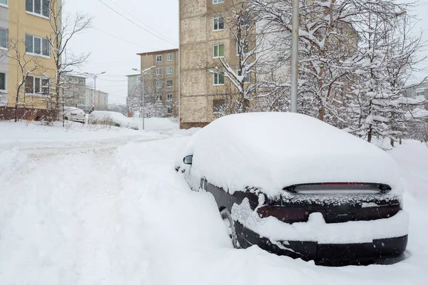 Car covered with snow after a snowfall. Snowdrifts around on the road ...