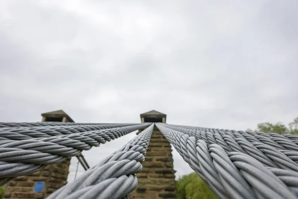Heavy steel wire cable leading to stone pier on historic bridge stone ...