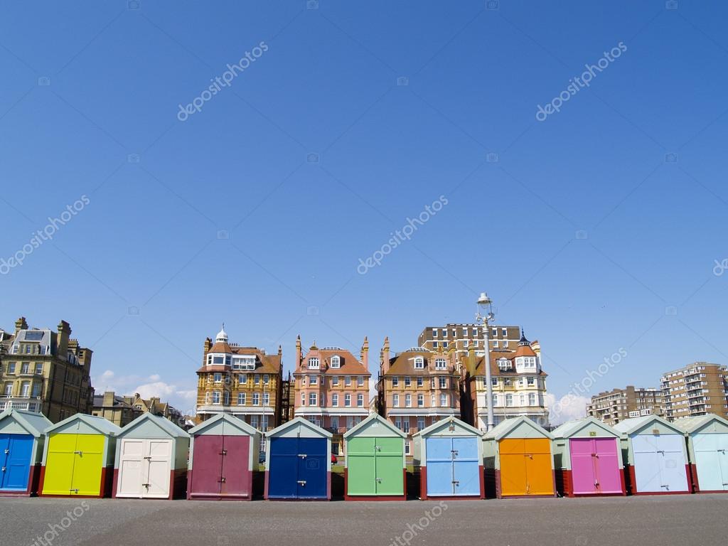 Brightly colored beach huts lined up along the beach with traditional ...