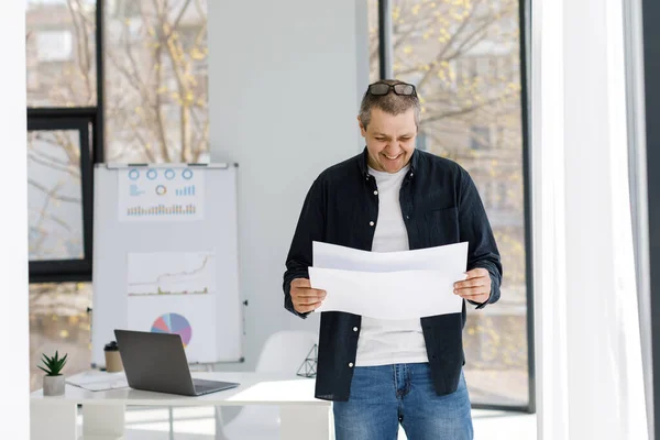 A man dressed in casual style works in the office and looking through ...