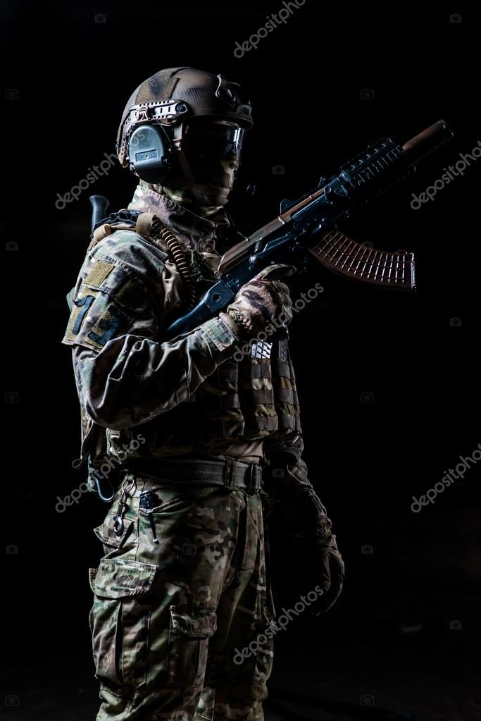 soldado equipado de pie en el perfil y la celebración de la máquina ...