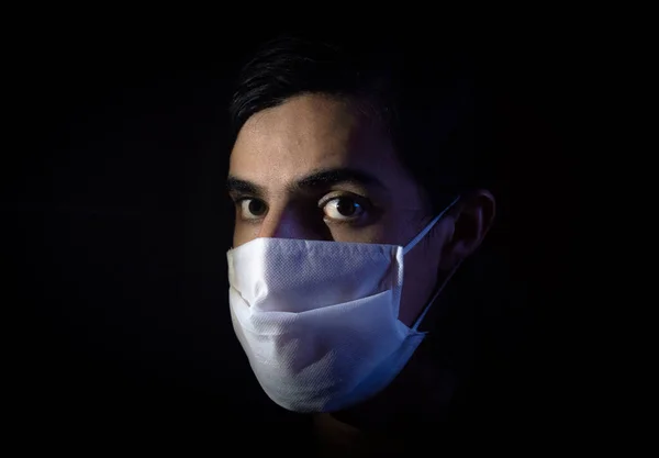 Portrait of a man with a disposable white face mask looking at the ...