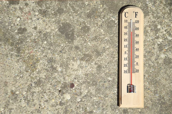 Thermometer on concrete background showing high summer temperature ...