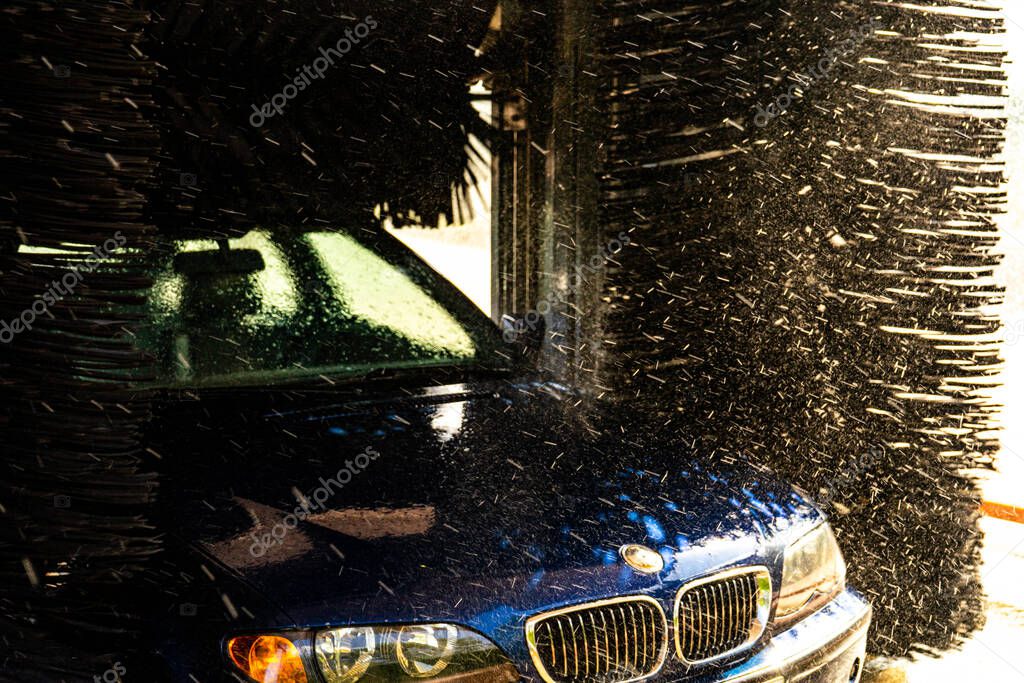 coche dándose un lavado con una máquina automática en la que se ve como ...