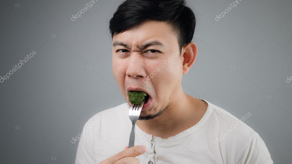 An Asian man eats broccoli. — Stock Photo © sevendeman #78991398