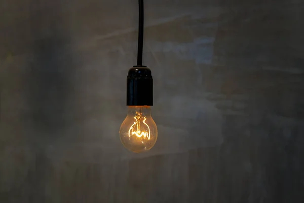 Glowing light bulb on the background of a gray blurred wall with ...