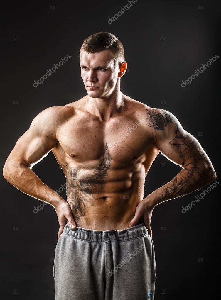 Muscular guy with tattoo. Isolated on dark background Stock Photo by ...