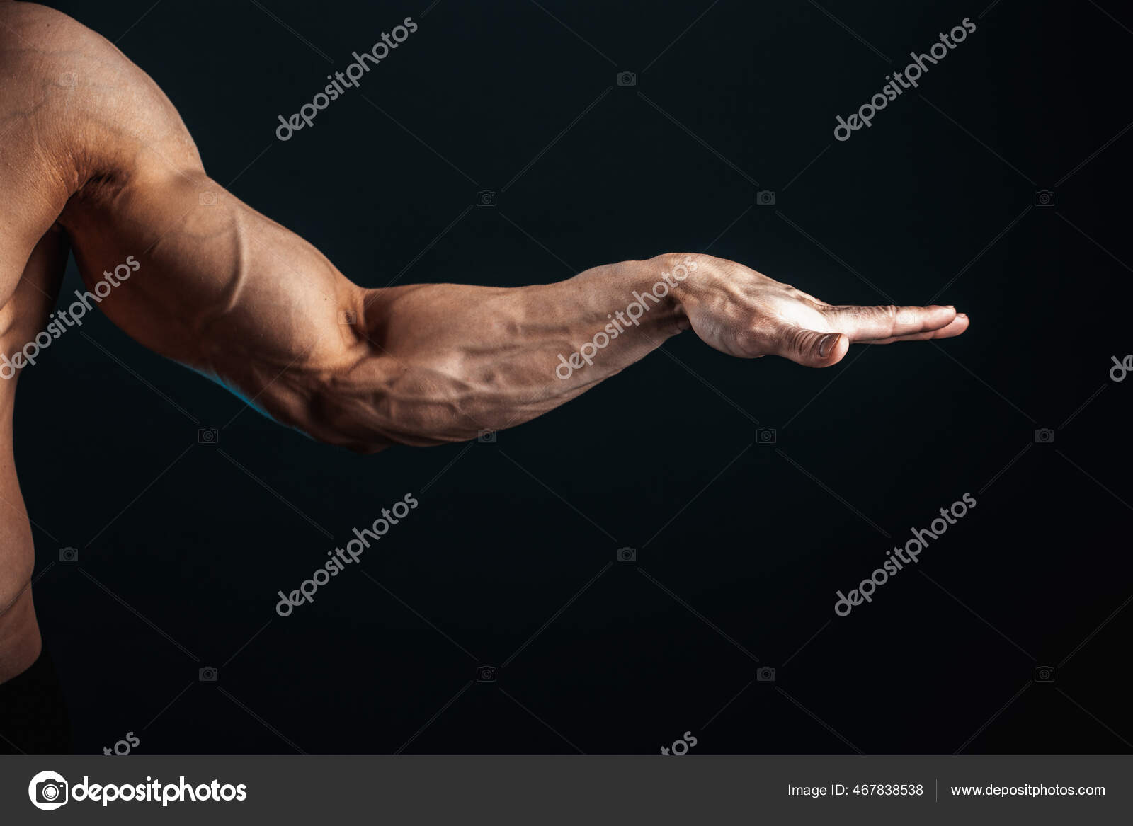 Tense arm, veins, bodybuilder muscles on a dark background, isolate ...