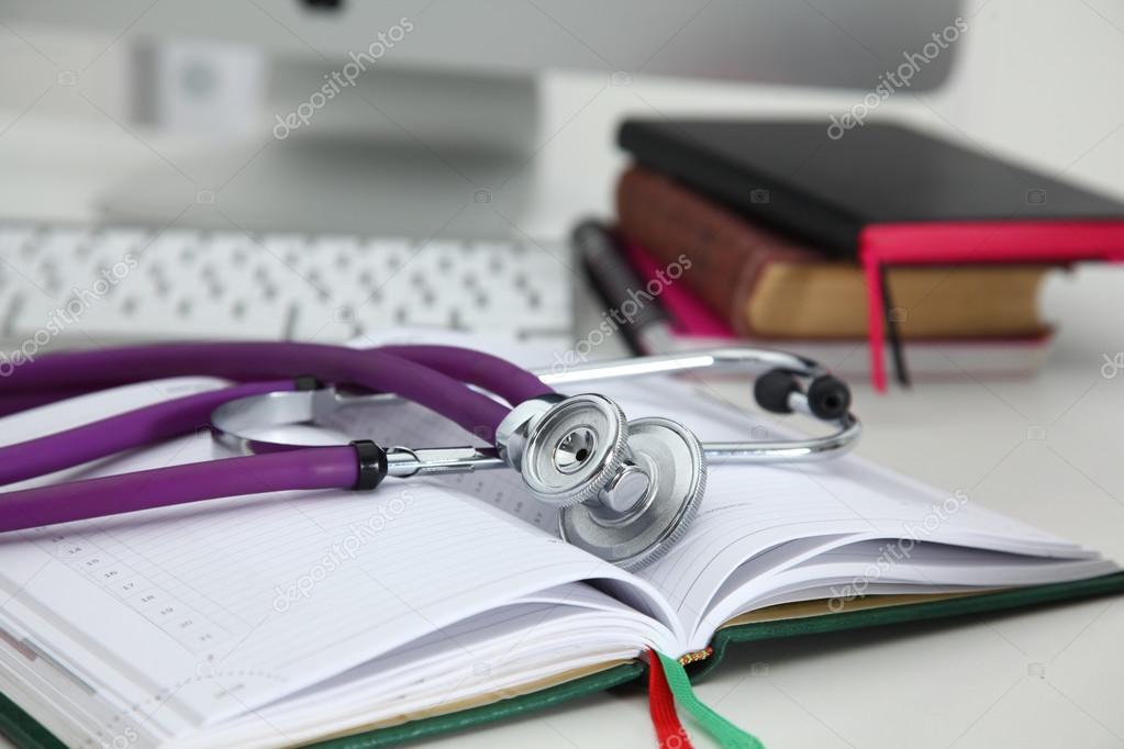 Stethoscope lying on a notebook computer in the background and books ...