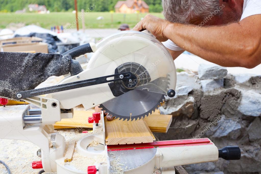 Framing contractor using a circular cut off saw to trim wood studs to ...