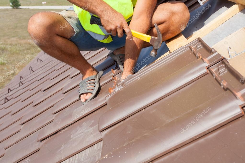 Hands of roofer laying tile on the roof. Installing natural red tile ...