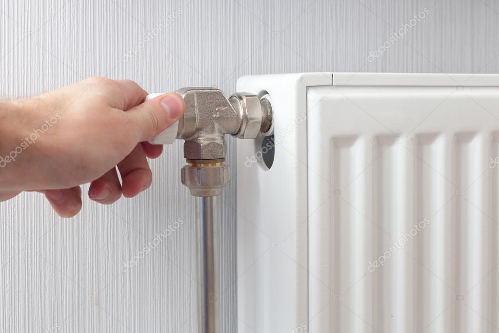 Radiator adjustment closeup. Man's hand adjusting radiator temperature ...