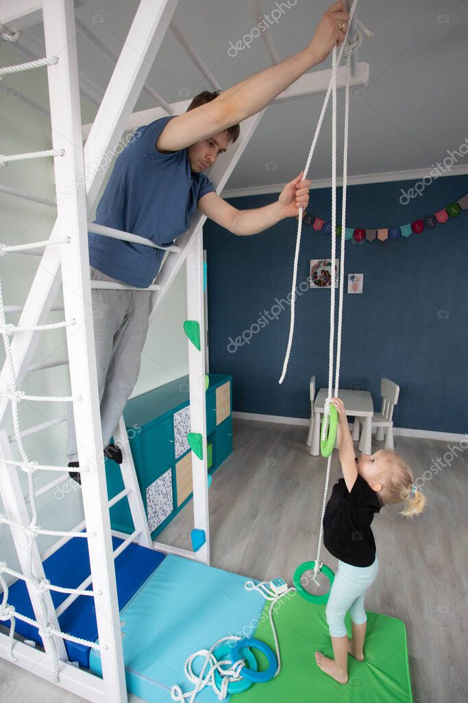 Familia construyendo complejo deportivo en casa. La hija está colgando ...
