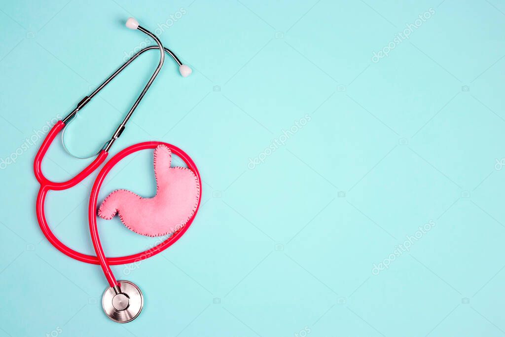 Modelo de estómago humano con estetoscopio sobre fondo azul ...