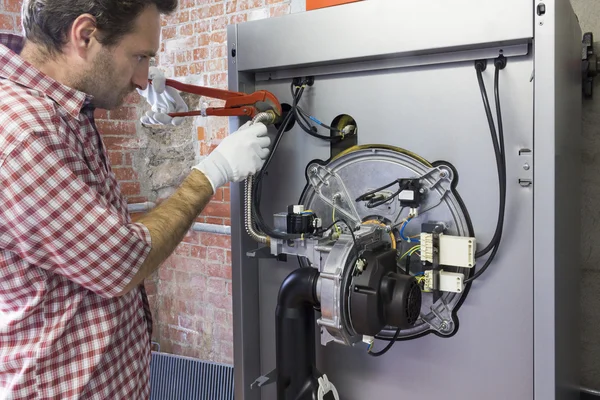 Plumber repairing a condensing boiler in the boiler room - Stock Image ...