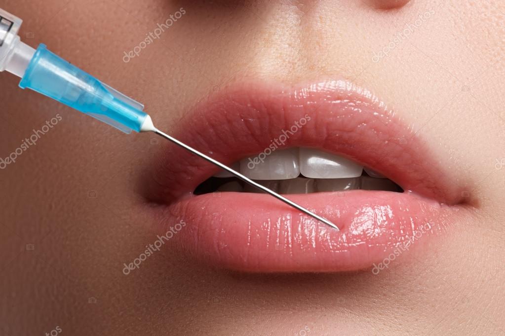 Primer plano de la hermosa mujer se inyecta en los labios. Labios ...
