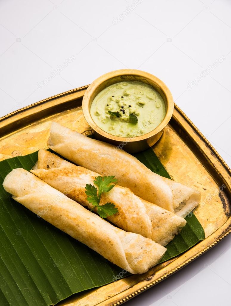 3 dosa rolls with coconut chutney in a brass tray over coconut leaf ...