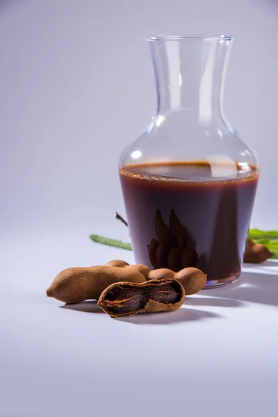 Raw tamarind fruits with sauce or puree in glass jar, imli chutney in ...