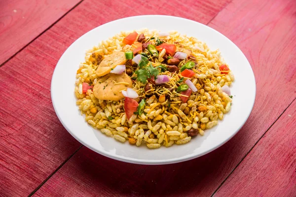 Indian snacks Bhel Puri served with chopped tomatoes, green chillies ...