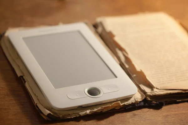 Black ereader with an old notebook in leather cover on wooden table ...