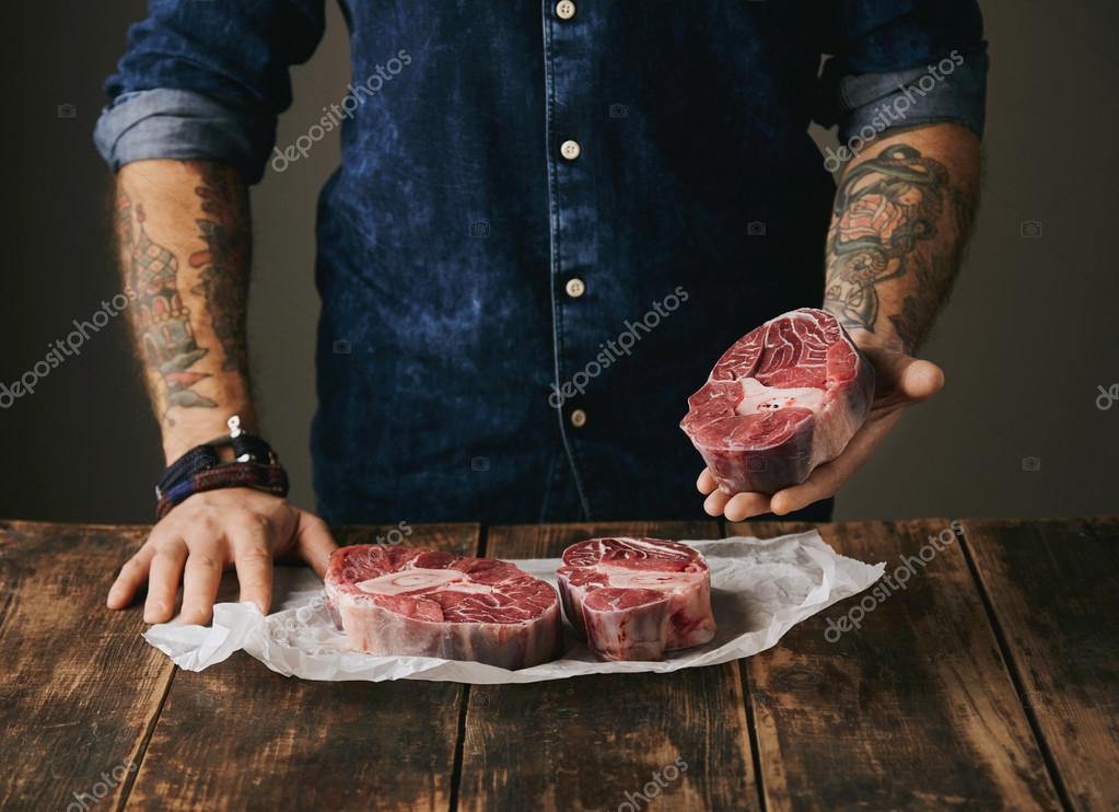 Butcher with tattooed hands offers raw meat steak — Stock Photo ...